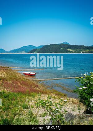 A small boat on the surface of a lake with the reflection of the sky ...