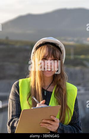 Female architecture taking notes on notepads looking building plan on ...