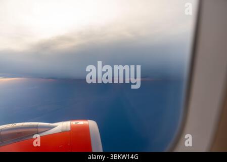 View of a sunset underneath a heavy stormy cloudbank from the window of ...