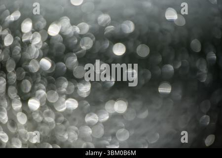 Abstract bokeh background featuring shimmering silver and gray light ...
