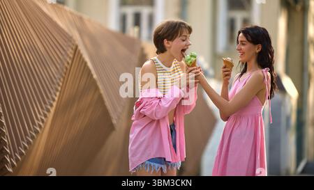 Cone connection. Two young women laughing and enjoying ice cream cones ...