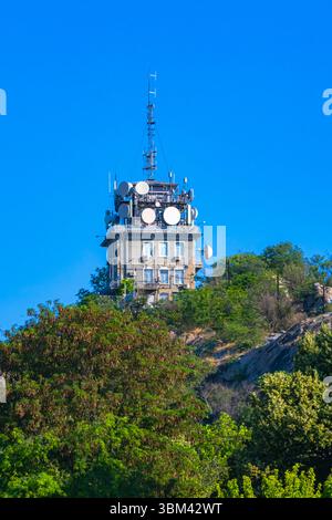 A tall communication tower stands prominently against a clear blue sky ...