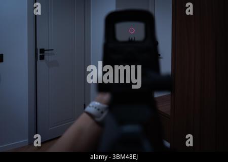 Aiming an assault rifle with a holographic sight in a forest, first ...