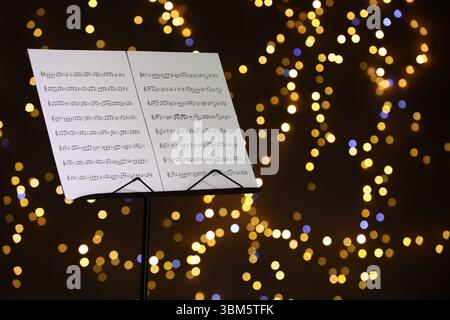 Note stand with music sheets against blurred lights, closeup. Bokeh ...