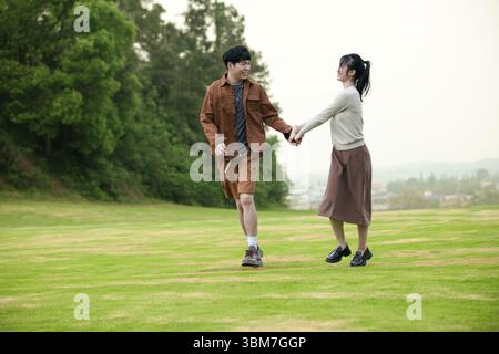 A young couple happily running and chasing each other on the lawn Stock ...