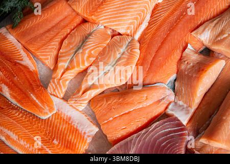 Vibrant raw salmon fillet on rustic wooden board, surrounded by fresh ...
