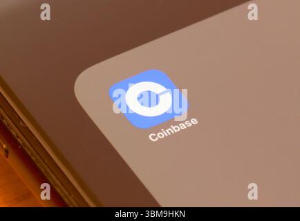 Logo of Coinbase crypto exchange on a phone screen against leather ...