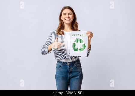 Young female volunteer holding recycle bin with garbage on green ...