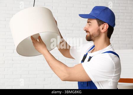 Happy male electrician changing light bulb in floor lamp at home Stock ...
