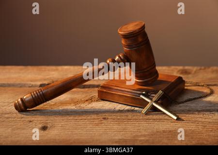 Judge's gavel and cross on wooden table against black background Stock ...