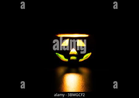 Pumpkin shape candle in a dark setting. Fire is glowing and making a ...