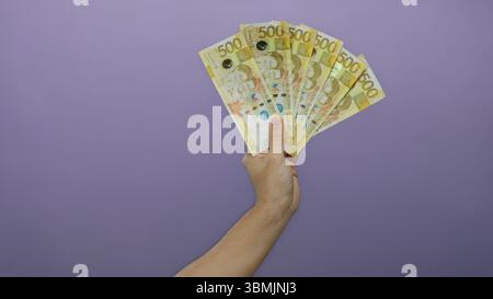 A hand holding several Philippine peso bills of various denominations ...