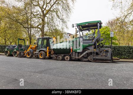 Asphalt paver and road roller machines on a construction site in a park ...