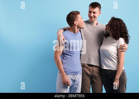 Three friends hugging on light blue background Stock Photo - Alamy