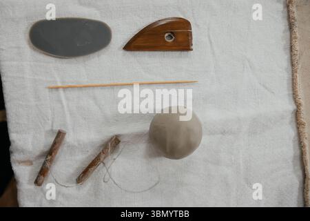 Round clay lump and ceramic hobby tools set on rustic table for pottery ...