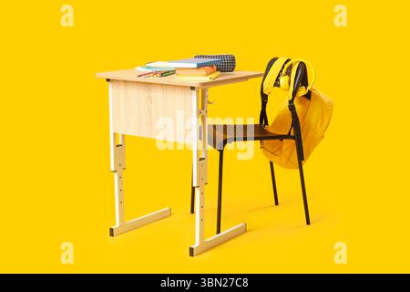 Yellow backpack with school stationery and headphones on bench outdoors ...