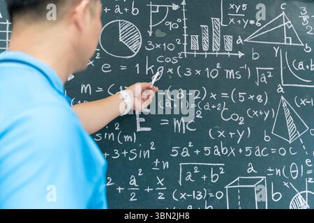 Teacher pointing at math formulas on chalkboard during online lesson in ...