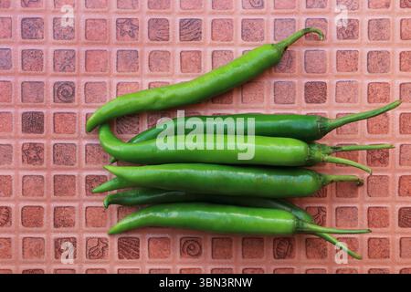 A small pile of vibrant green hot chili peppers rests on a textured ...