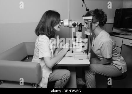 Female doctor examines young womans eye using professional vision ...