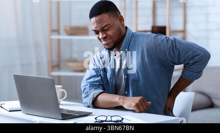 African Guy Having Backache Massaging Aching Back At Workplace Indoor ...