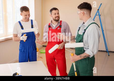 Team of male decorators with paint rollers in room Stock Photo - Alamy