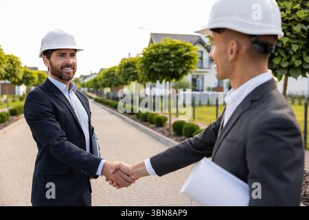 Construction team celebrating project with handshake Stock Photo - Alamy