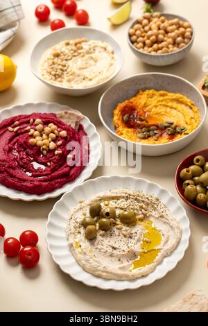 Different types of hummus in bowls and plates. Beetroot, pumpkin ...