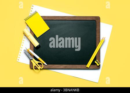 School supplies on a black chalkboard background. Composition with ...