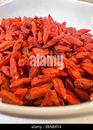 Plate with red dried goji berries on wooden table Stock Photo - Alamy