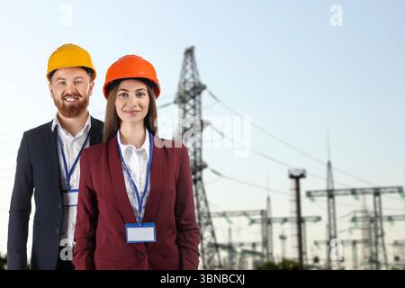 Power engineers in hard hats holding drafts and laptop against ...