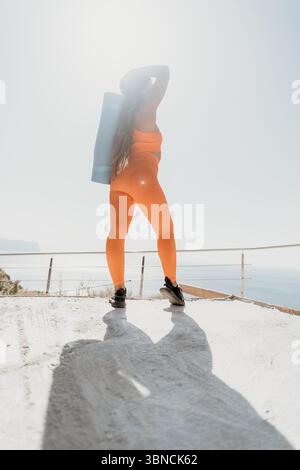 A woman in an orange sports bra and shorts stretches her arm while ...