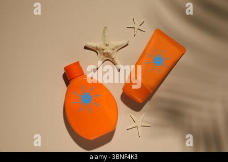 Sunscreen products and sea stars on beige background, top view. Bottle ...