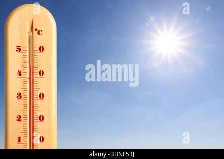 Extremely high temperature on thermometer against blue sky on sunny day ...