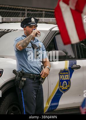 A Philadelphia PD police officer in front of a squad car in ...