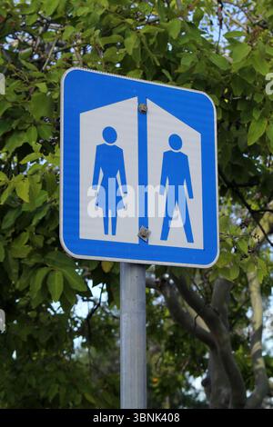 A blue restroom sign with male and female symbols is mounted on a ...