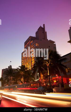 Busy city street Miami. Illuminated buildings line the street, cars ...