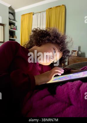 smiling child in cozy sleepwear with christmas toy on red background ...