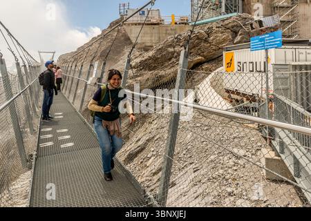Tourists cross the Titlis Cliff Walk suspension bridge on the Titlis in ...