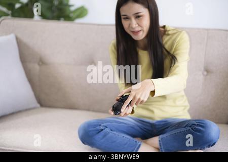 Young Asian female gamer playing video game with controller relaxing on ...