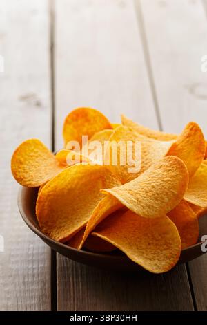 Crispy potato chips in a clay plate on old kitchen table Stock Photo ...