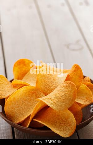 Crispy potato chips in a clay plate on old kitchen table Stock Photo ...