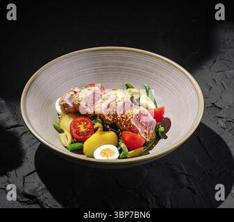 A vibrant and healthy tuna salad presented in a beige bowl, featuring ...