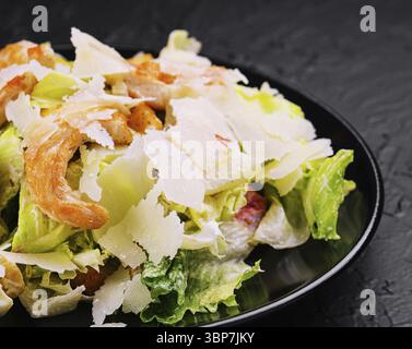 Plate with delicious Caesar salad on color wooden background, closeup ...