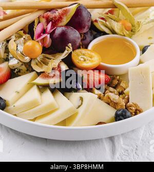 Elegant cheese board with assorted cheeses, fruits, nuts, and honey ...