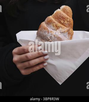 cropped view of girl holding croissant near parents and fresh vegetable ...