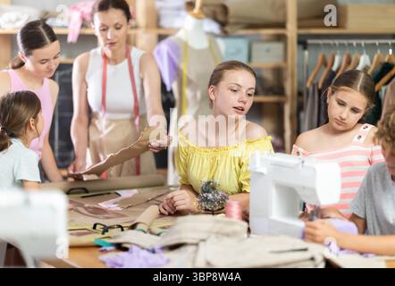 Teen girl watching peer sewing at machine during class Stock Photo - Alamy