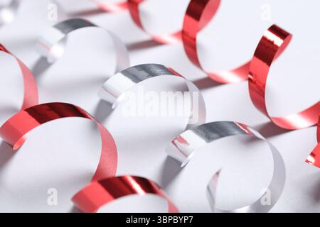 Shiny serpentine streamers on white background, above view. Space for ...