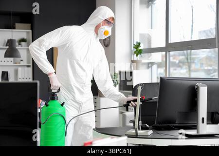 Male worker disinfecting workplace in office Stock Photo - Alamy