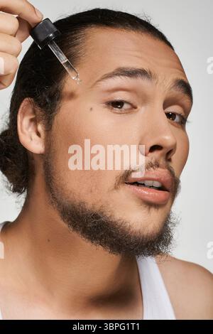 Young man applying face serum at home Stock Photo - Alamy