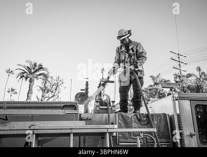 Fallen trees and damaged homes line a street Tuesday, April 14, 2020 ...